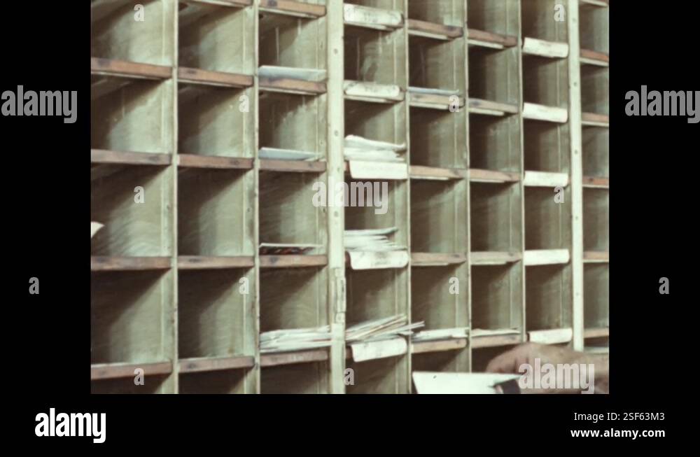 1960s: Man in post office sorts mail into boxes. Man loads bags of mail ...