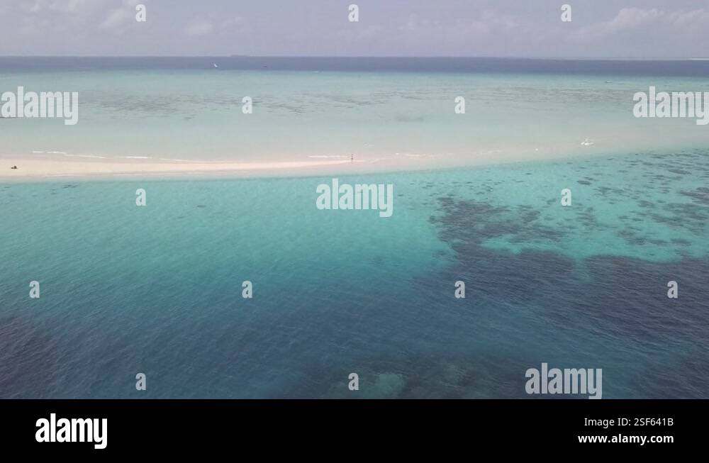 Lone tourist enjoys solitude on sandy spit, coral reefs and warm water ...