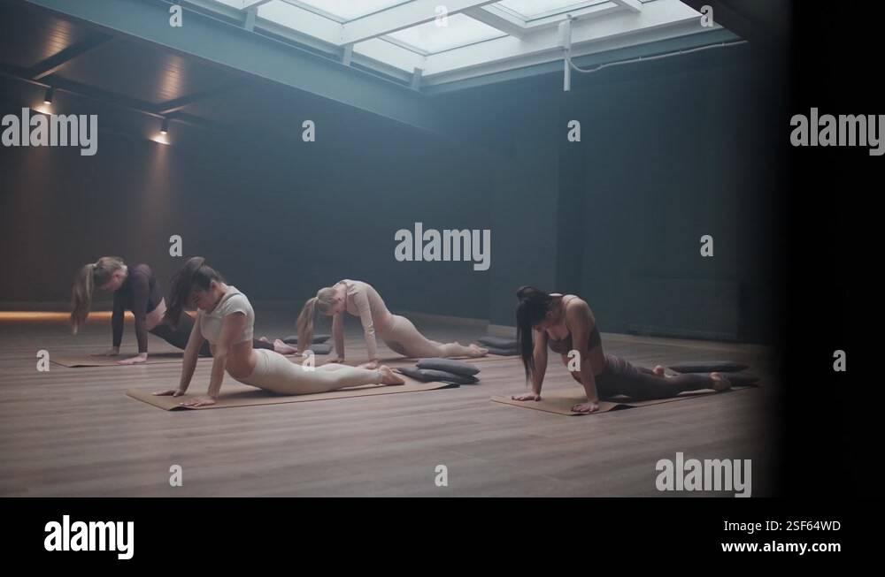 Cinematic, group of girls doing yoga in a dark room, flexible females performs a Stock Video ...