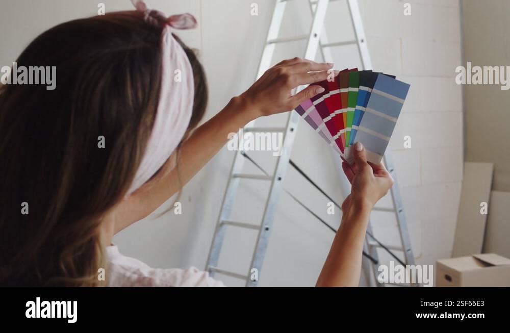 Woman choosing color for painting walls, holding palette of shades ...