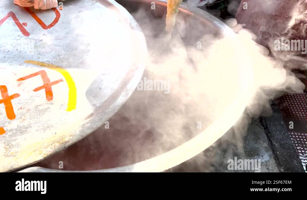 Adding paste of spices in the boiling pot of mixed curry vegetable for ...