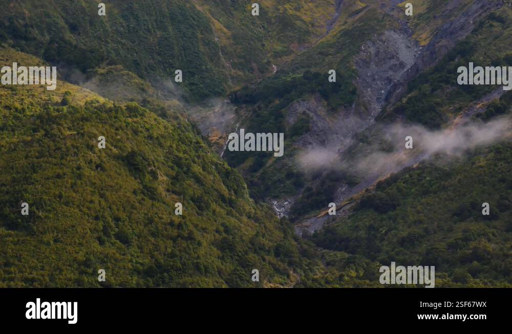 Top down shot of natural ravine canyon with trees and flying clouds ...