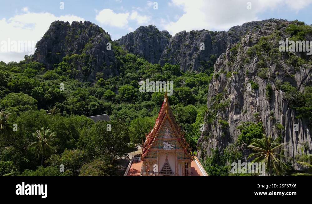 Ascending aerial footage of the Wat Khao Daeng with limestone mountains ...