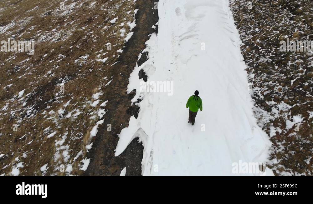 Aerial: man walking on a snow covered path. Zenital shot Stock Video ...
