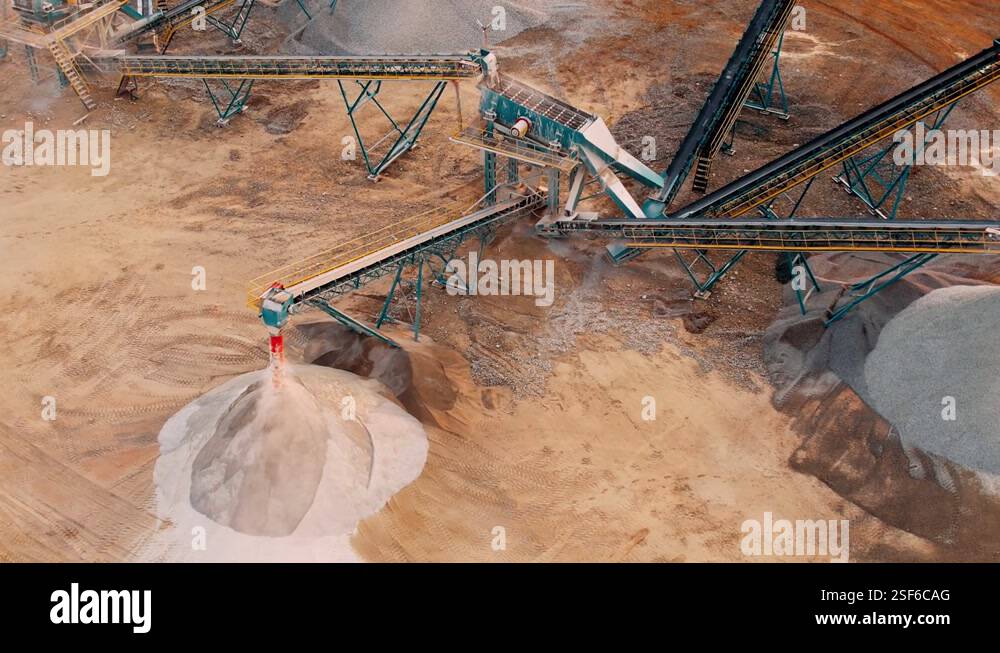 Mining industry concept. Crushed stones falling from a moving line at a ...