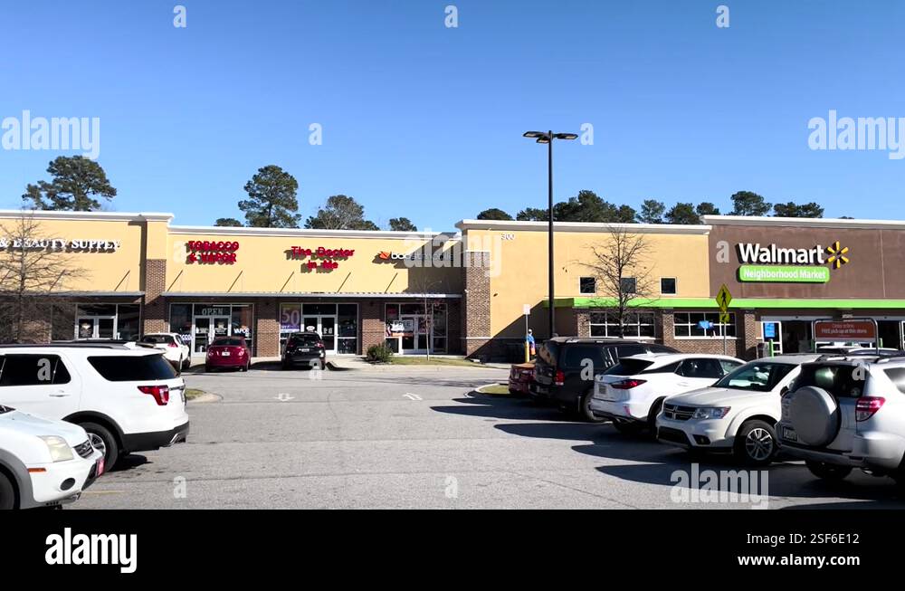 Pan of Walmart grocery store building people and parking lot clear blue ...