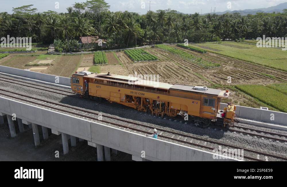 Several construction workers are compacting the railroad track using ...