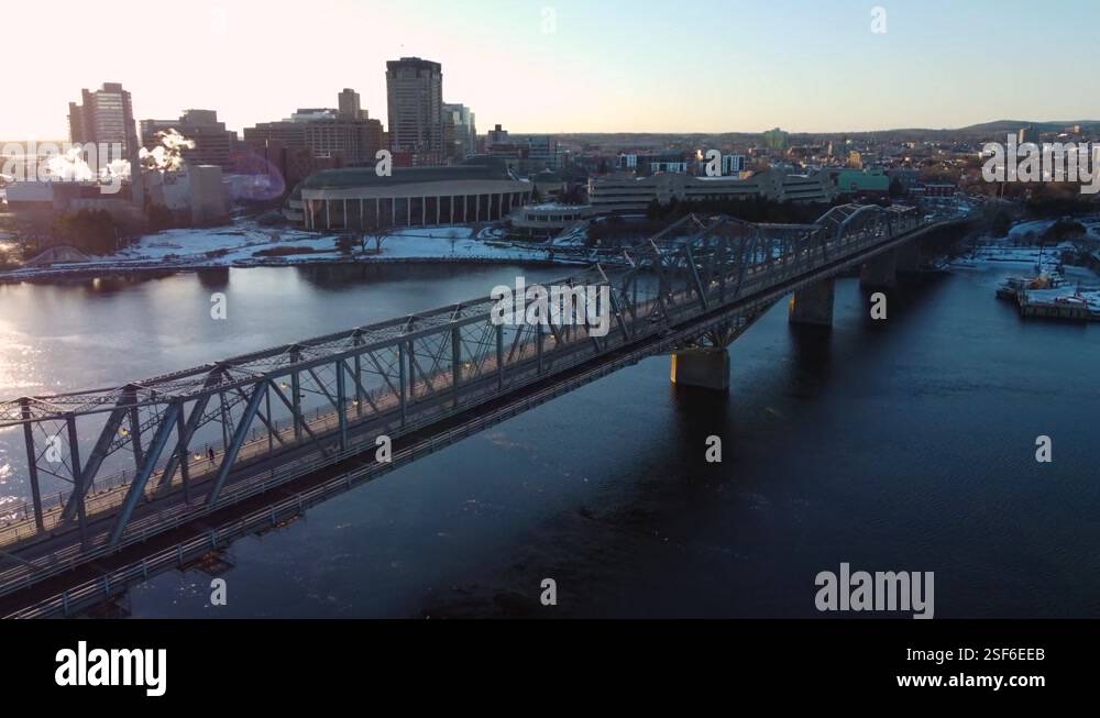 Panning aerial view of a metal bridge and a medium sized Canadian city ...