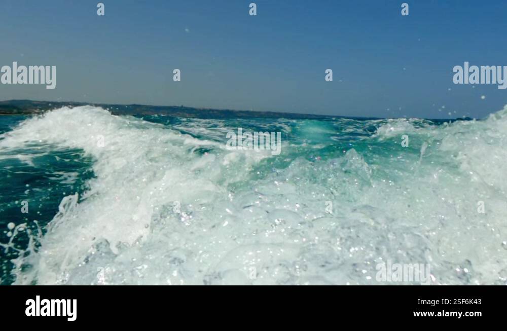 Low-angle water surface pov of motorboat wake trail over blue seawater ...