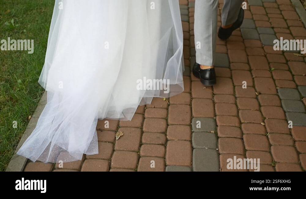 close-up of the legs of the groom and the dress of the bride going ...