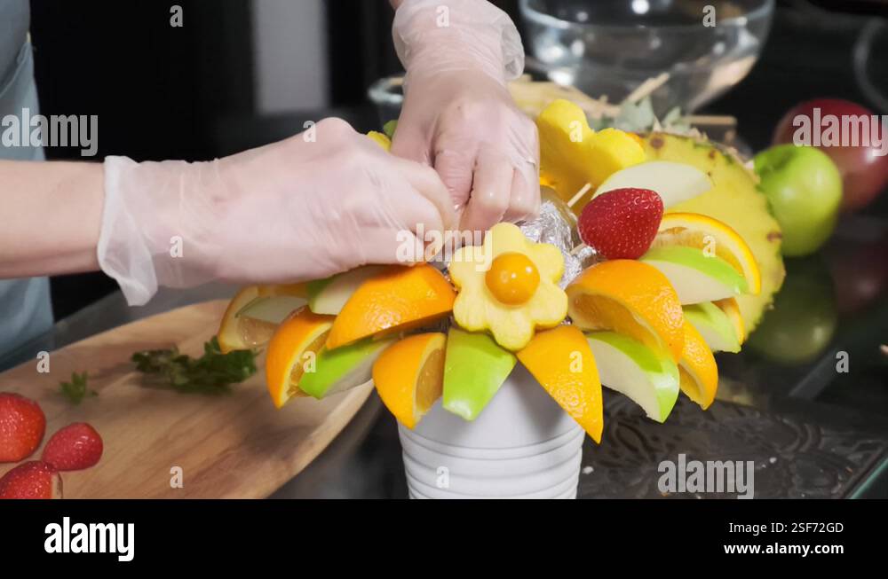 The girl creates a fruity bouquet by attaching a strawberry to a stick ...