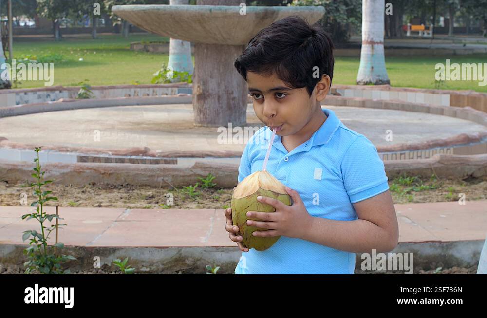 A well dressed young boy drinking tender coconut water - a refreshing ...