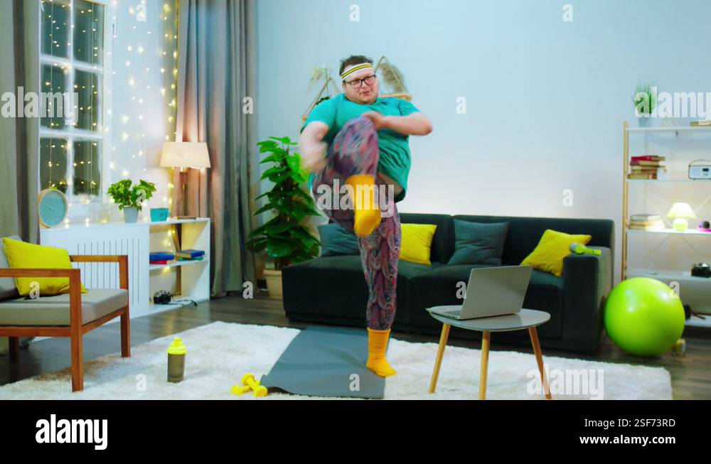 Funny fat guy in the living room using laptop to do a online course for ...