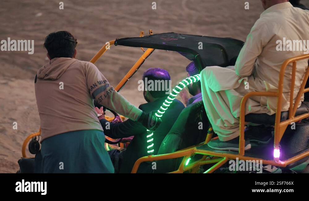 Male Guiding Group Of Friends On Dune Buggy On Karachi Beach In Evening ...