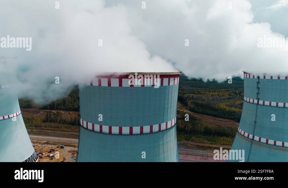 Flying over the smoke-filled cooling tower of a nuclear power plant ...