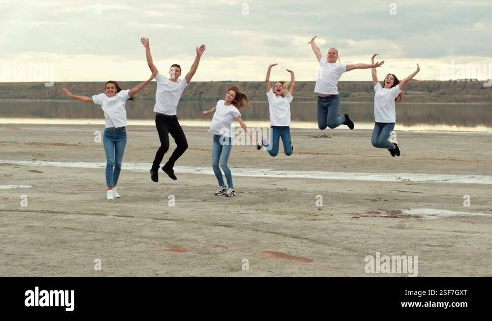Group of friends jumps and waves hands on flat river bank Stock Video ...