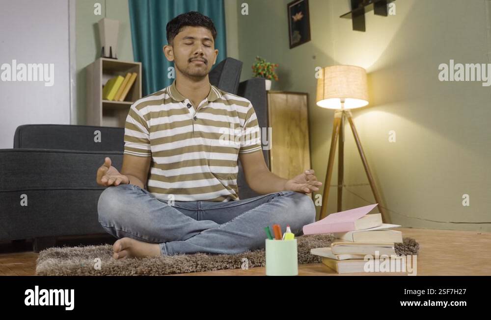 Young man meditating in front of books before reading for examination ...