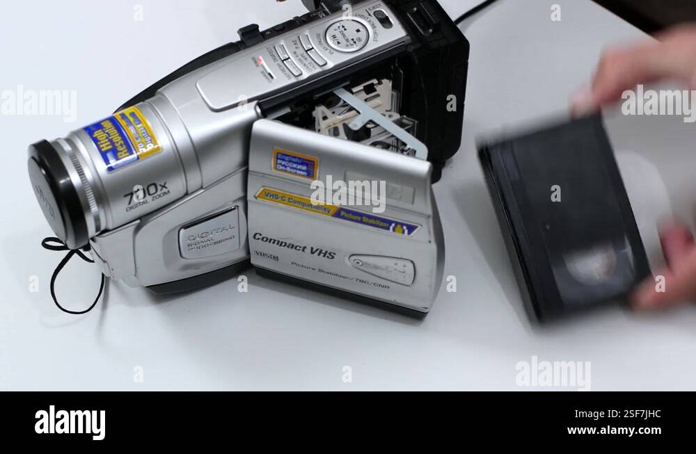A man is changing a videotape to record in a '90s JVC camcorder. Retro ...