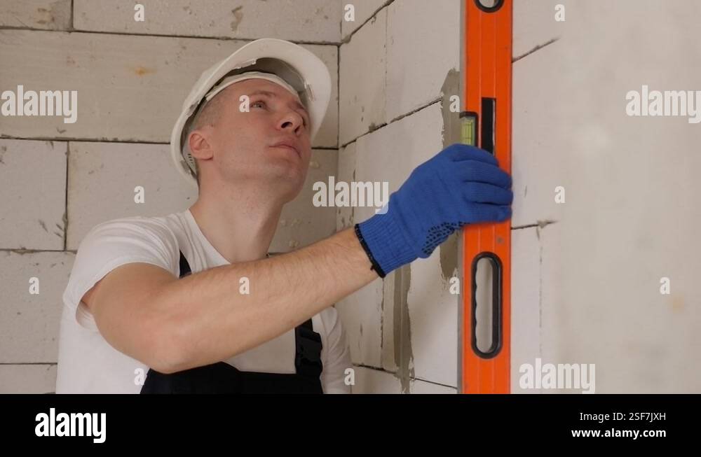 Foreman worker using a spirit level and marking the concrete wall with ...