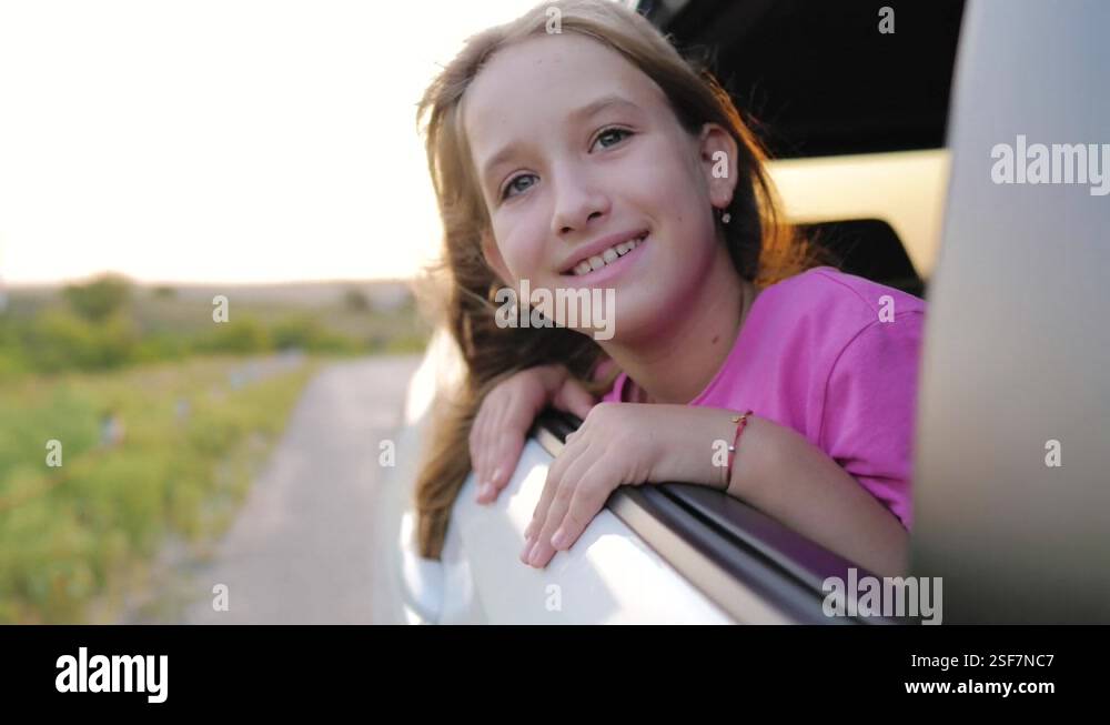 Happy family travel. Little girl leaning out of car window waving hand ...