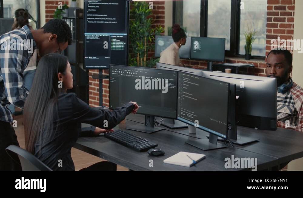 Mixed team of programmers analyzing source code pointing at screens ...