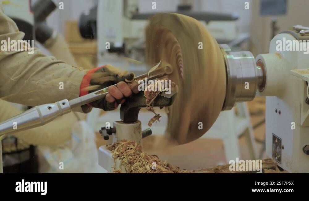 Slow motion: man holding chisel for shaping piece of wood on lathe ...