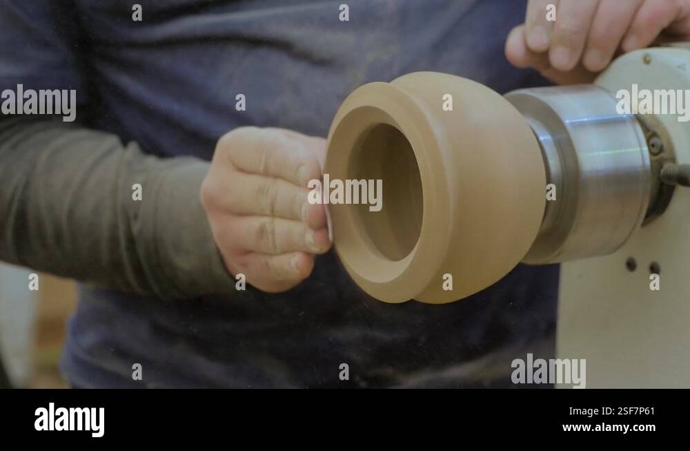 Slow motion: man using sandpaper for sanding piece of wood on lathe ...