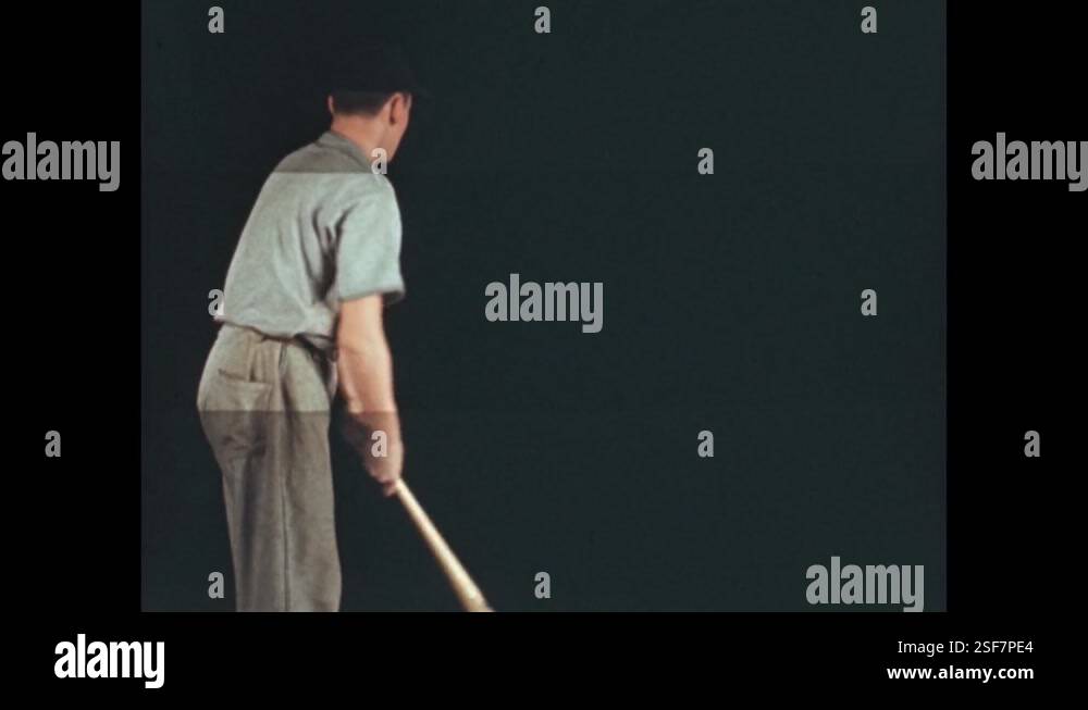 1940s: Rear view of baseball player swinging bat, posing with bat, dark ...