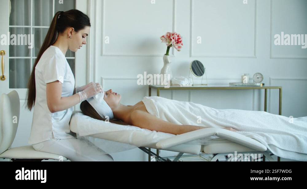 Curing skin problems. Female cosmetologist looking at client's face and ...