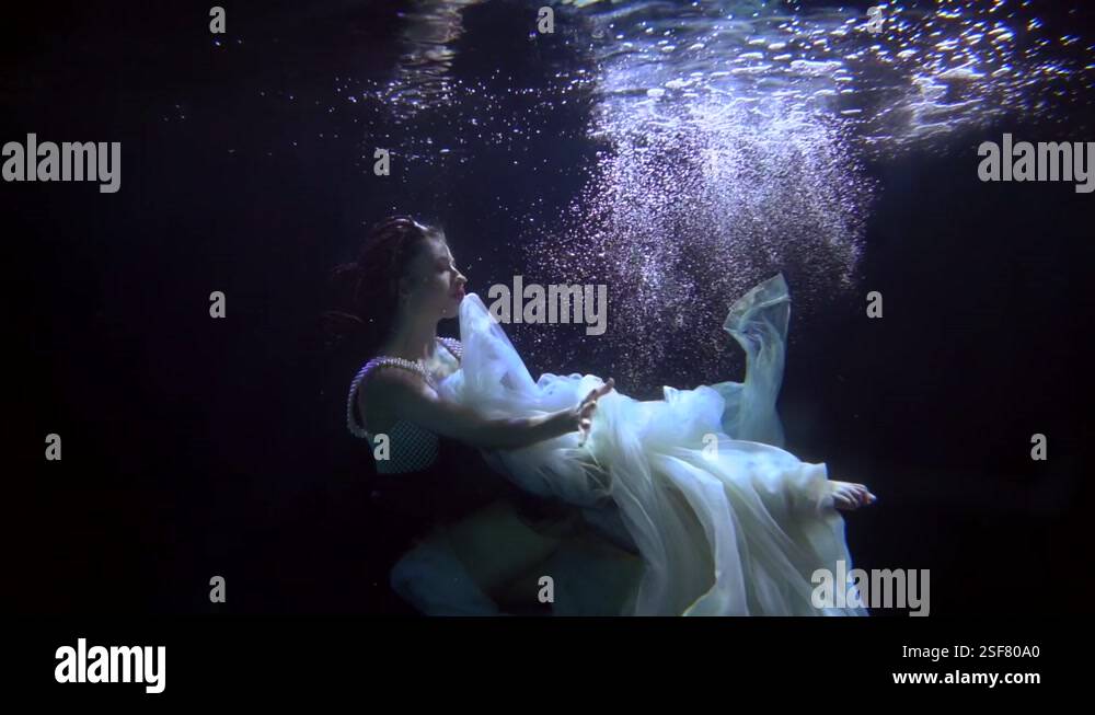 underwater shot in pool, woman is sinking and diving to depth, romantic ...