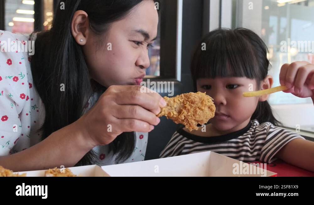 Happy mother and child eating fried chicken together at a fast food ...