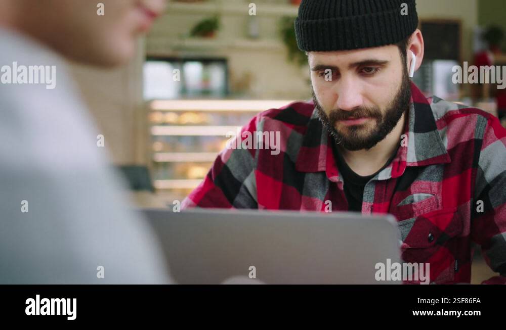 Closeup to the camera portrait of a young man working on the laptop at ...