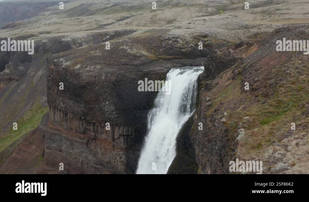 Slide and pan shot of water rolling over edge of rock and falling along ...