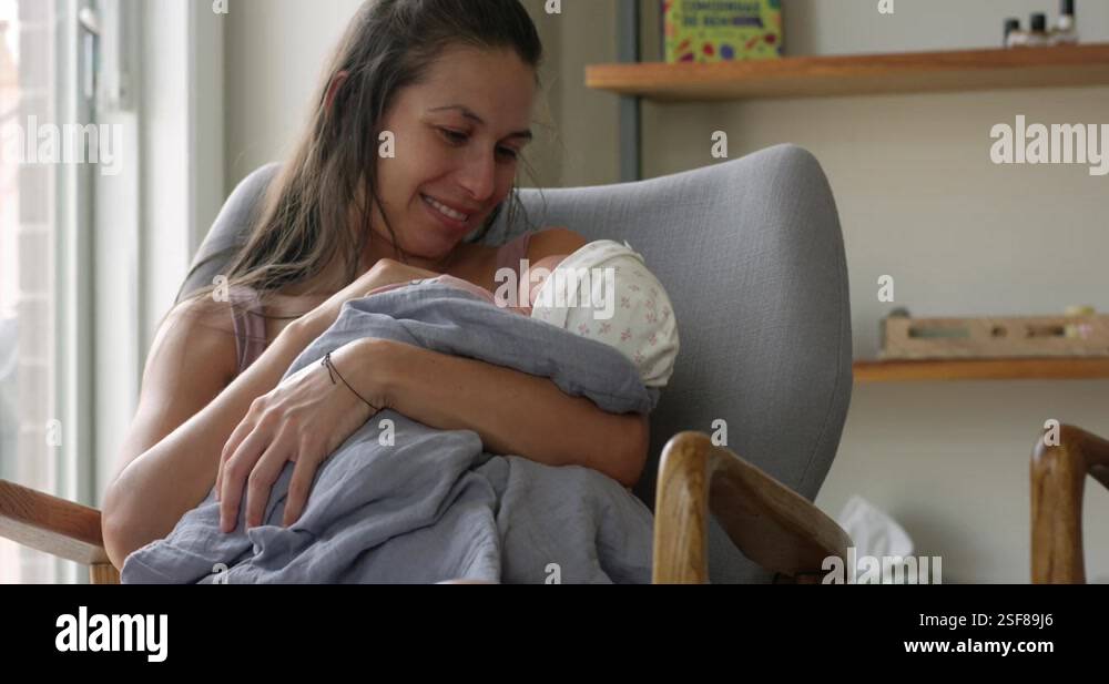 New mother smiles as she holds and stares at her new born baby girl ...
