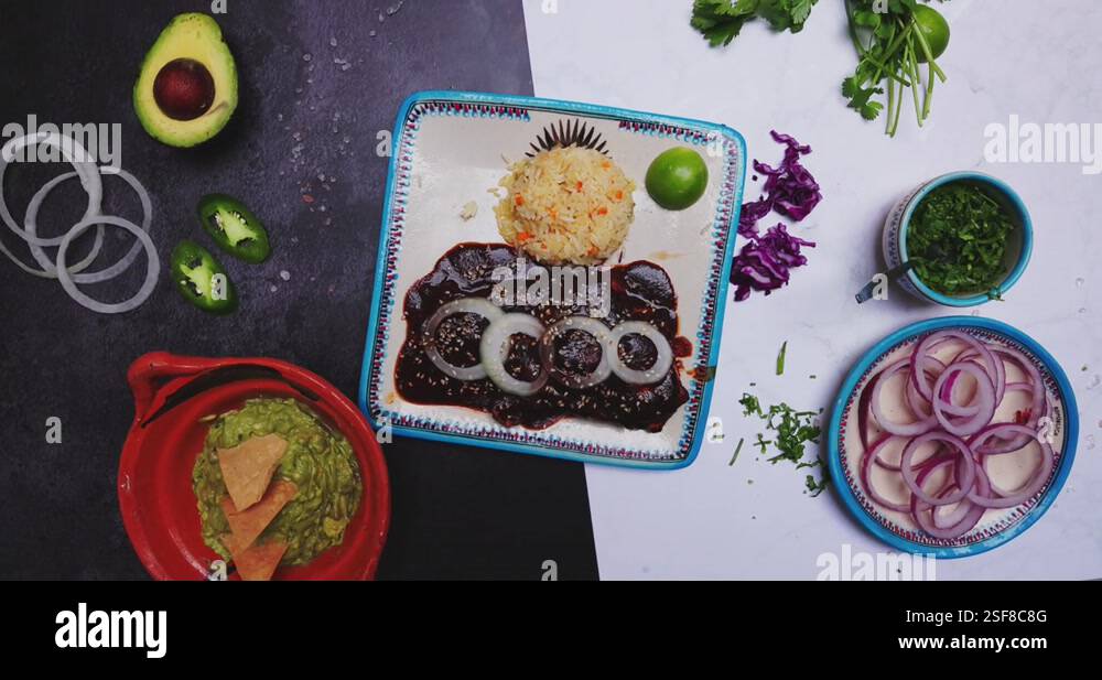 Delicious mole, rice, onion slices, and more food on two-color surface ...