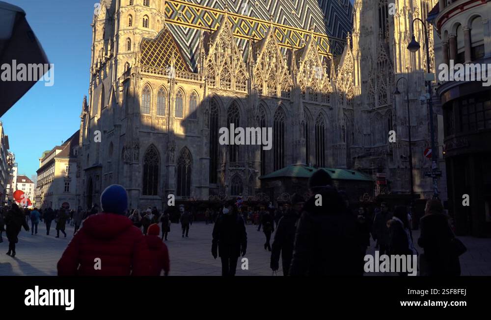 Static shot - People wearing facemasks walking in front of St. Stephen ...