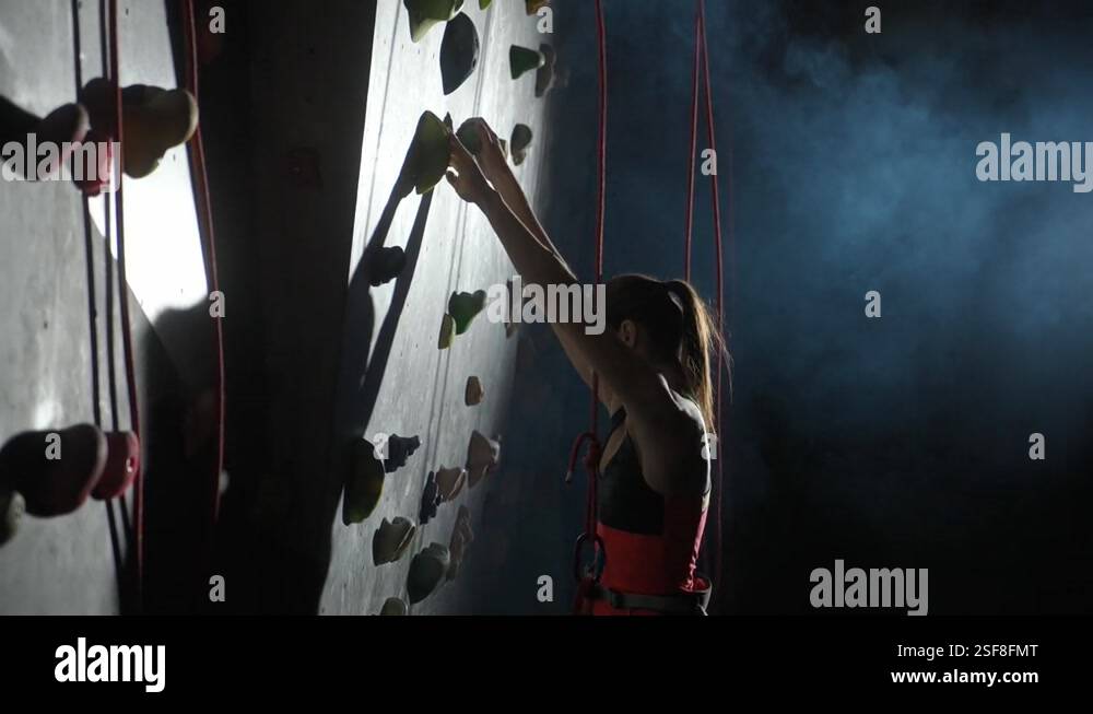 Side view, young female climber training on a climbing wall, practicing ...