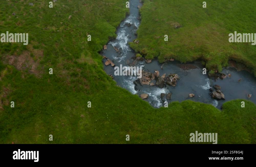 Descending footage of water in creek flowing between stones in riverbed ...