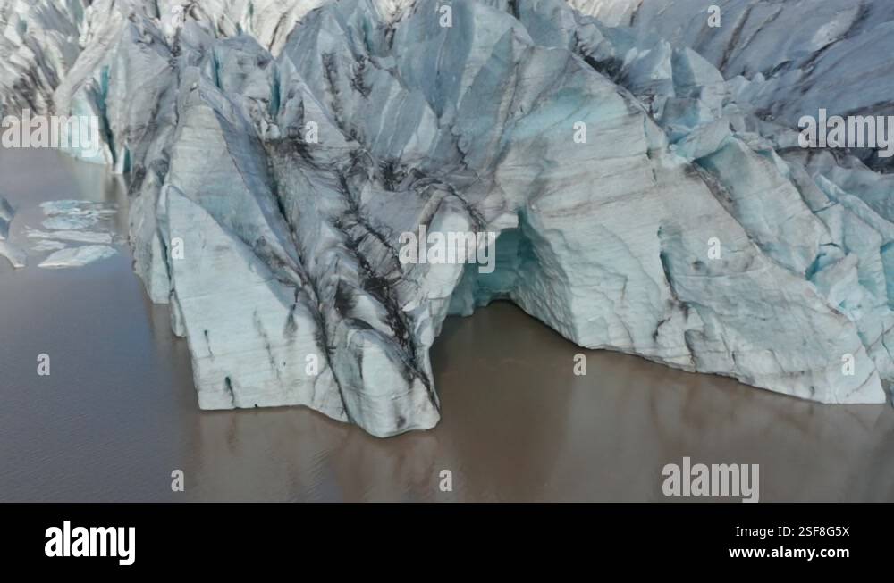 Slide and pan aerial shot of ice blocks on front of glacier standing in ...