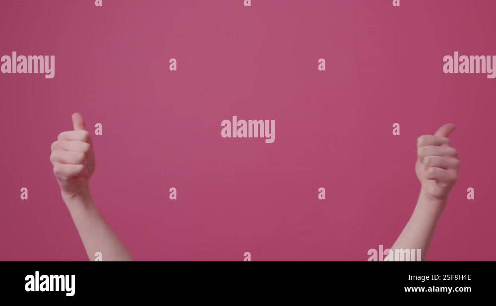 Woman points thumb up against an isolated pink background.Approval hand ...