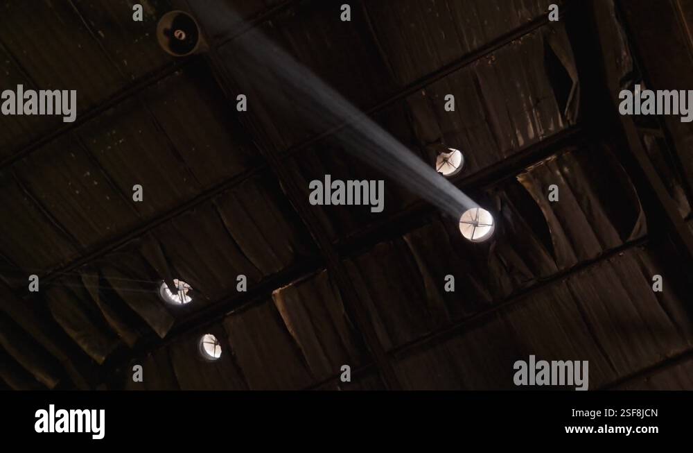Panning shot of old dilapidated warehouse ceiling with rays of sunlight ...