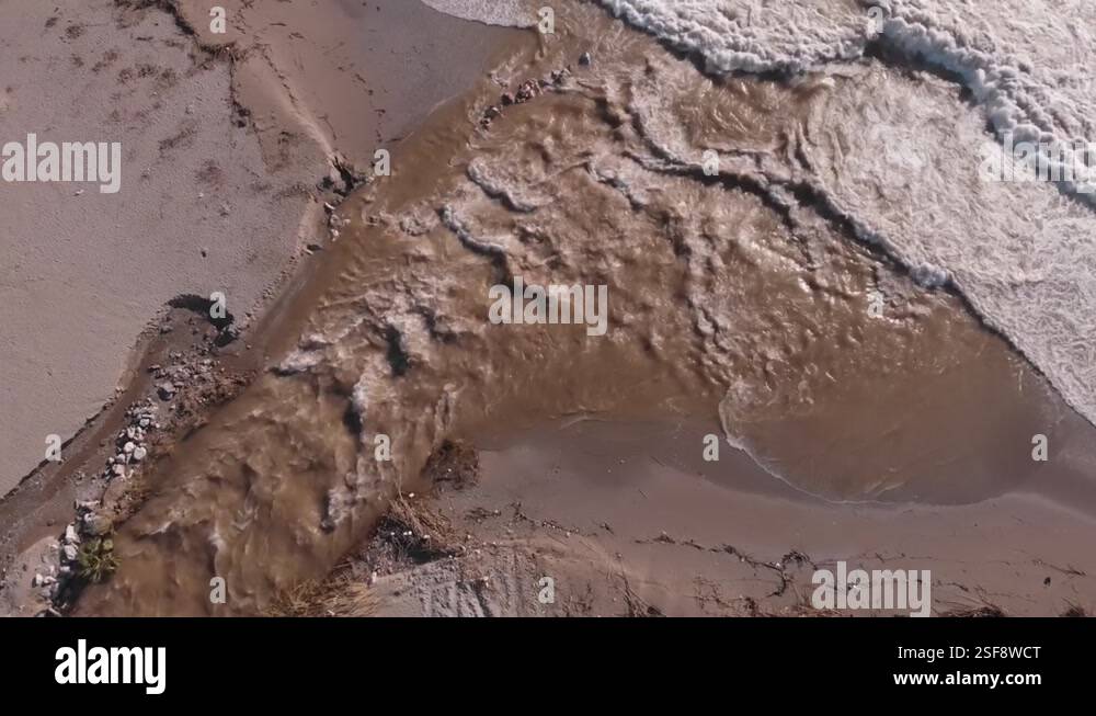 Muddy river with dirty water and debris flowing into sea. Beach and sea ...