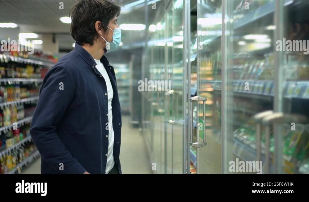 Male consumer choosing fresh food and walking in supermarket or market ...