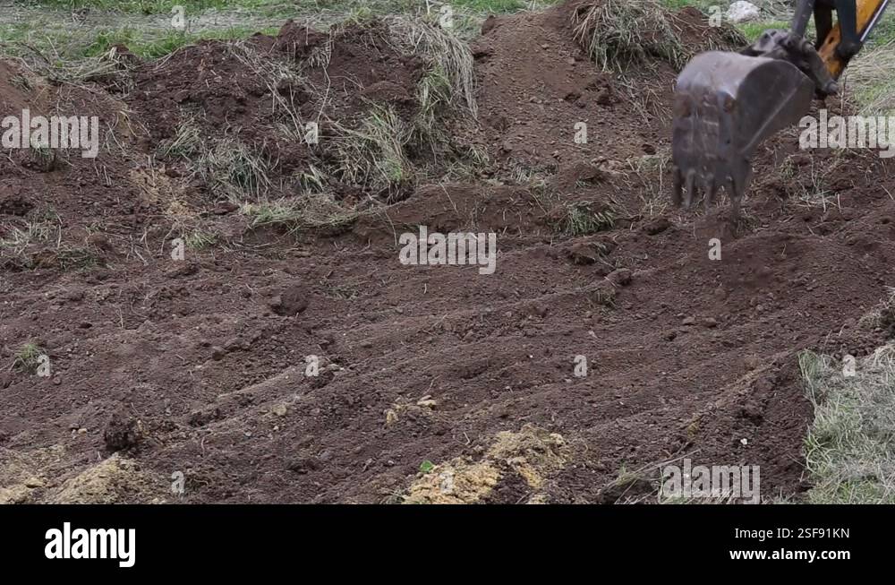 excavator bucket scoop removes the top layer of soil and levels it ...