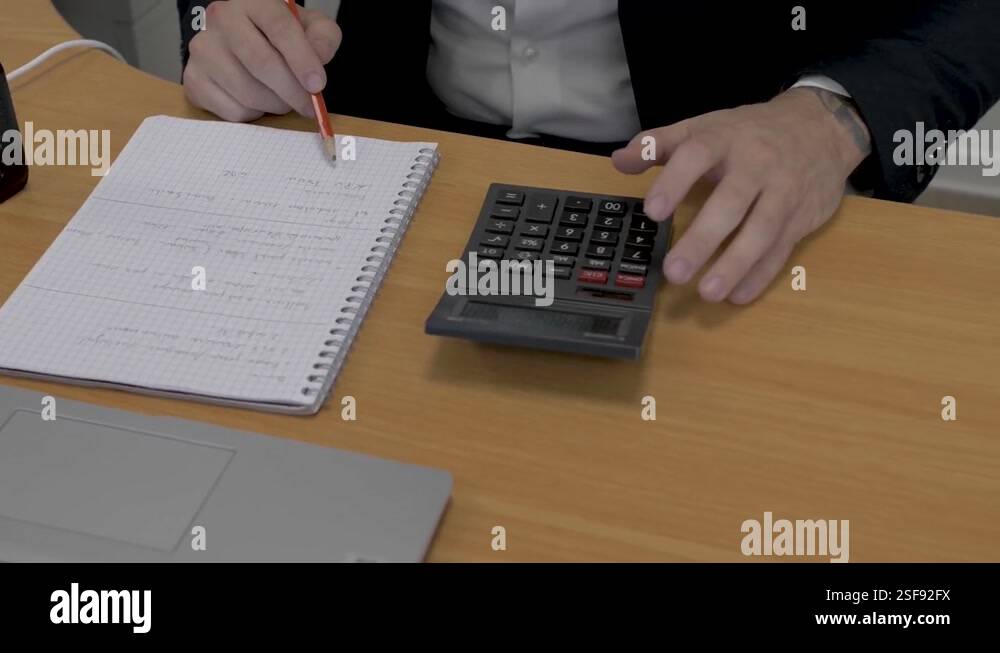 Accountant tabulating with a calculator and a notepad wearing a suit ...