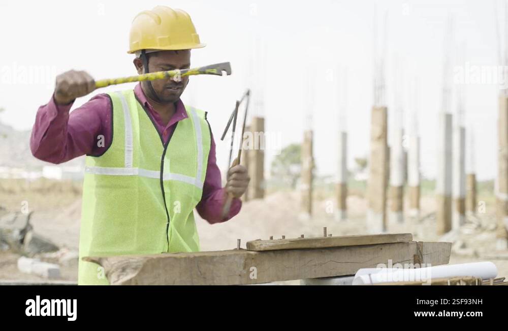 Indian construction worker with hard hat bending steel rod at workplace ...