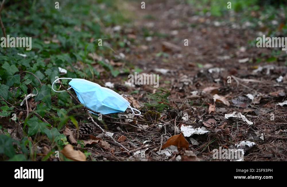 Person walking past a dirty face mask thrown on the side of the trail ...