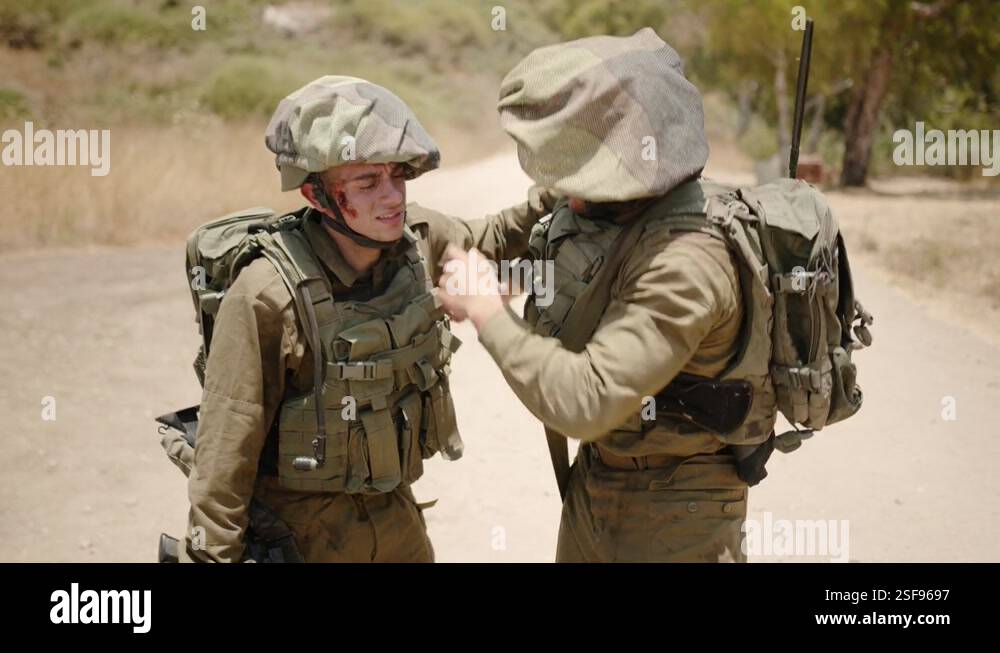 Male soldier helping his team mate with a bleeding right leg to put his ...