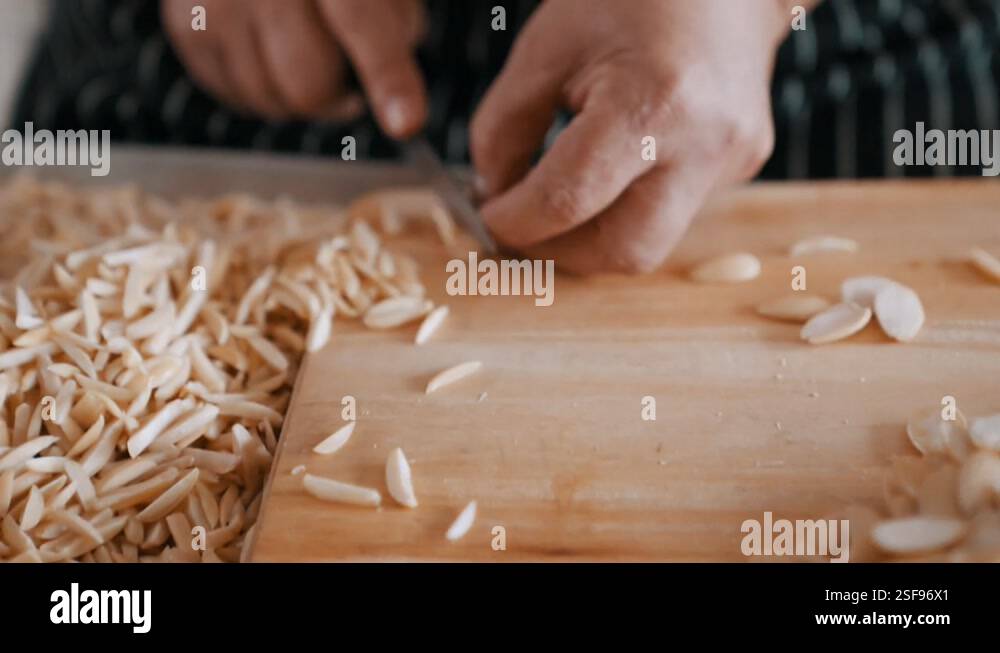 Hand Cutting Blanched Almonds into Slivers with Knife on Wooden Board ...