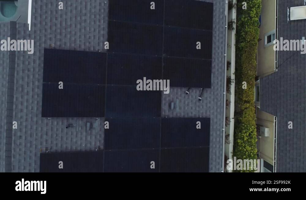 Slow aerial flyover looking down on solar panels installed on a rooftop ...